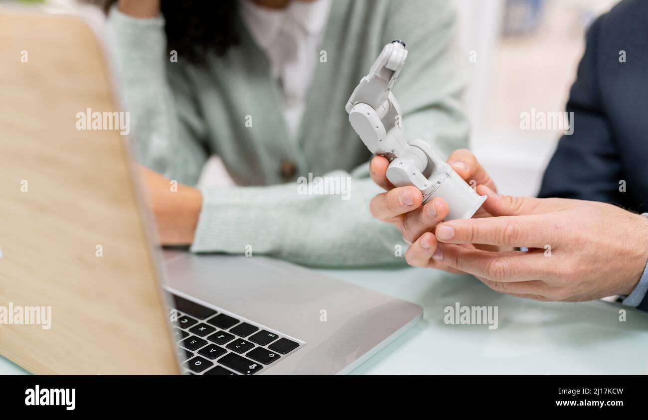 Hand of businessman showing robotic arm through video call on laptop in ...