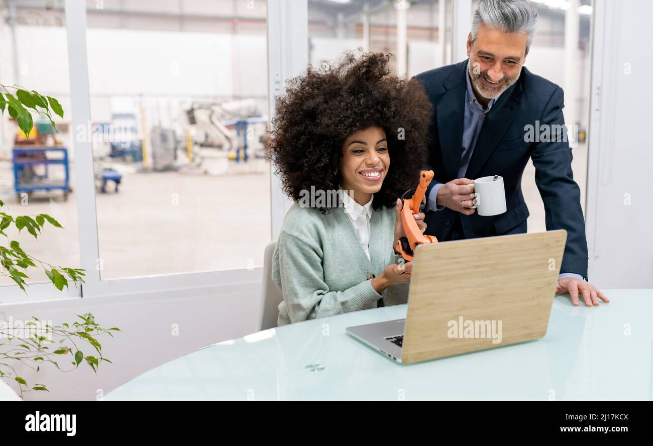 Smiling engineer showing model of robotic arm through video call on ...