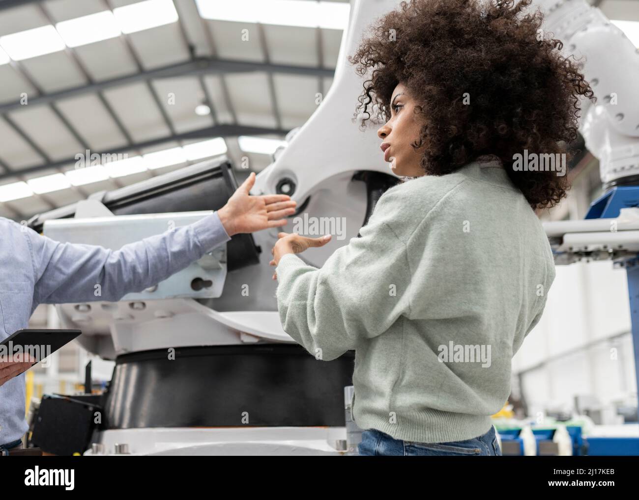 Developer discussing with colleague about robotic arm in factory Stock ...
