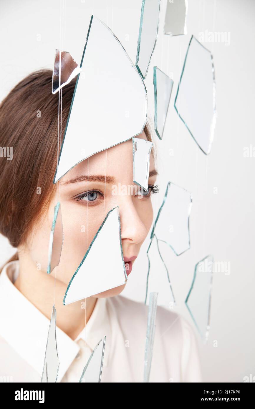 Young woman behind broken mirror Stock Photo - Alamy