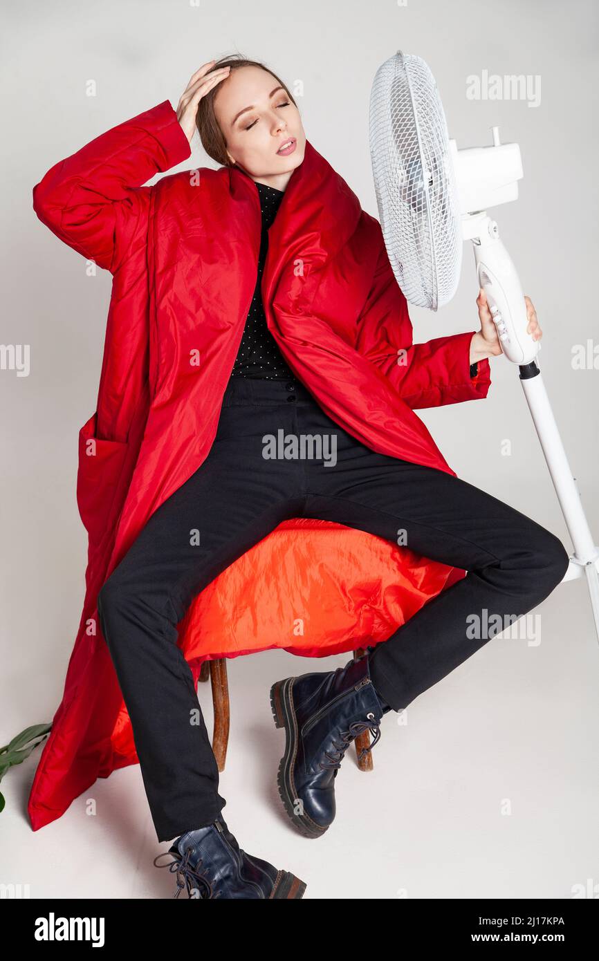 Beautiful young woman with eyes closed holding electric fan sitting ...