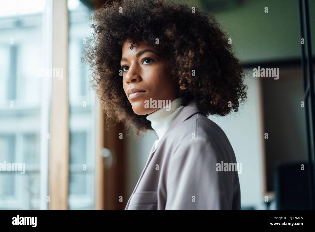 Thoughtful businesswoman with curly hair at work place Stock Photo - Alamy