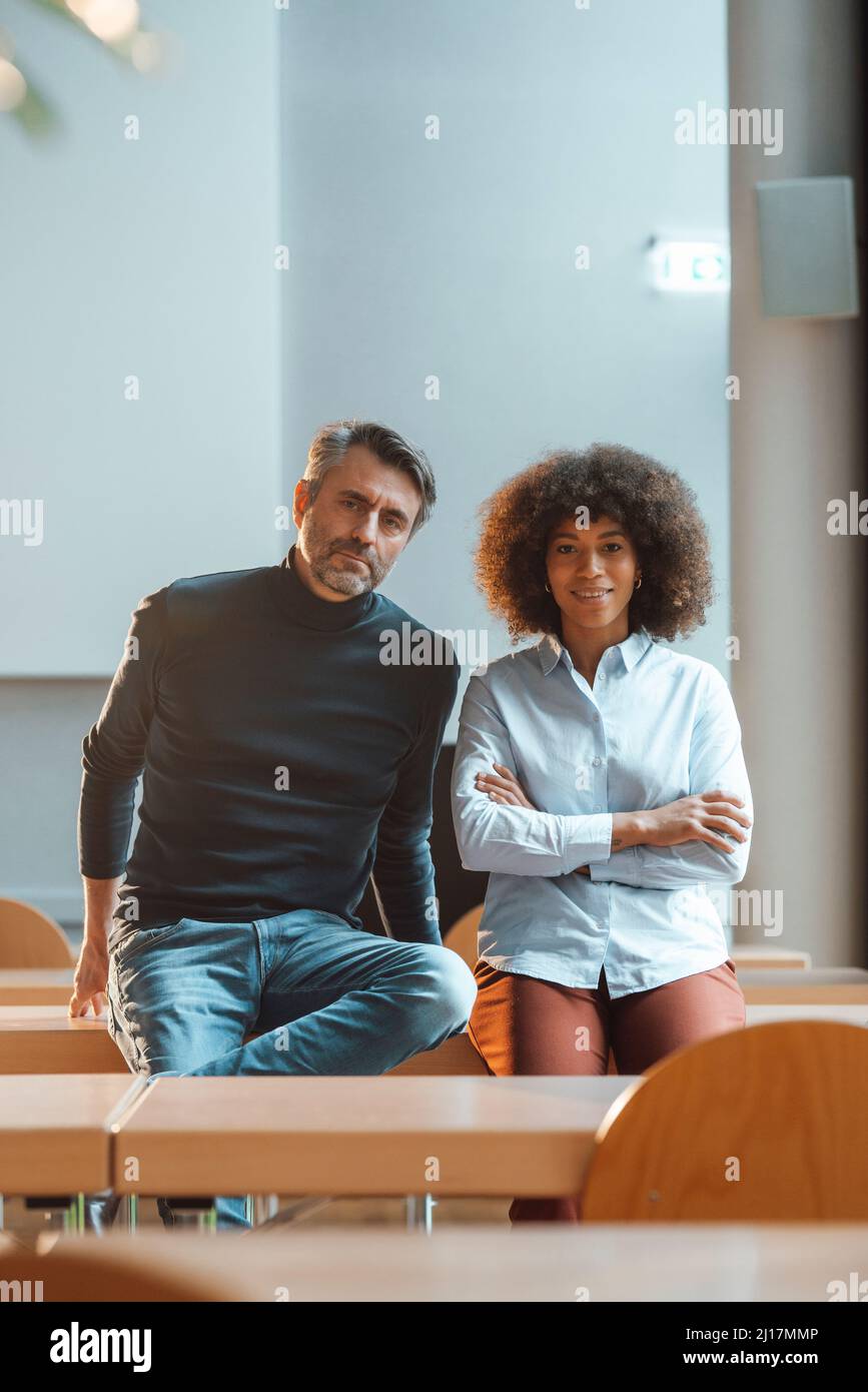 Working woman with arms crossed by colleague at work place Stock Photo ...