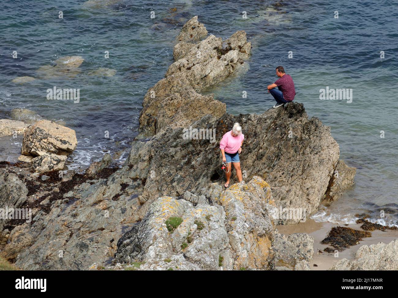 People climbing large rocks on Porth Towyn beach nearTudweiliog on the ...