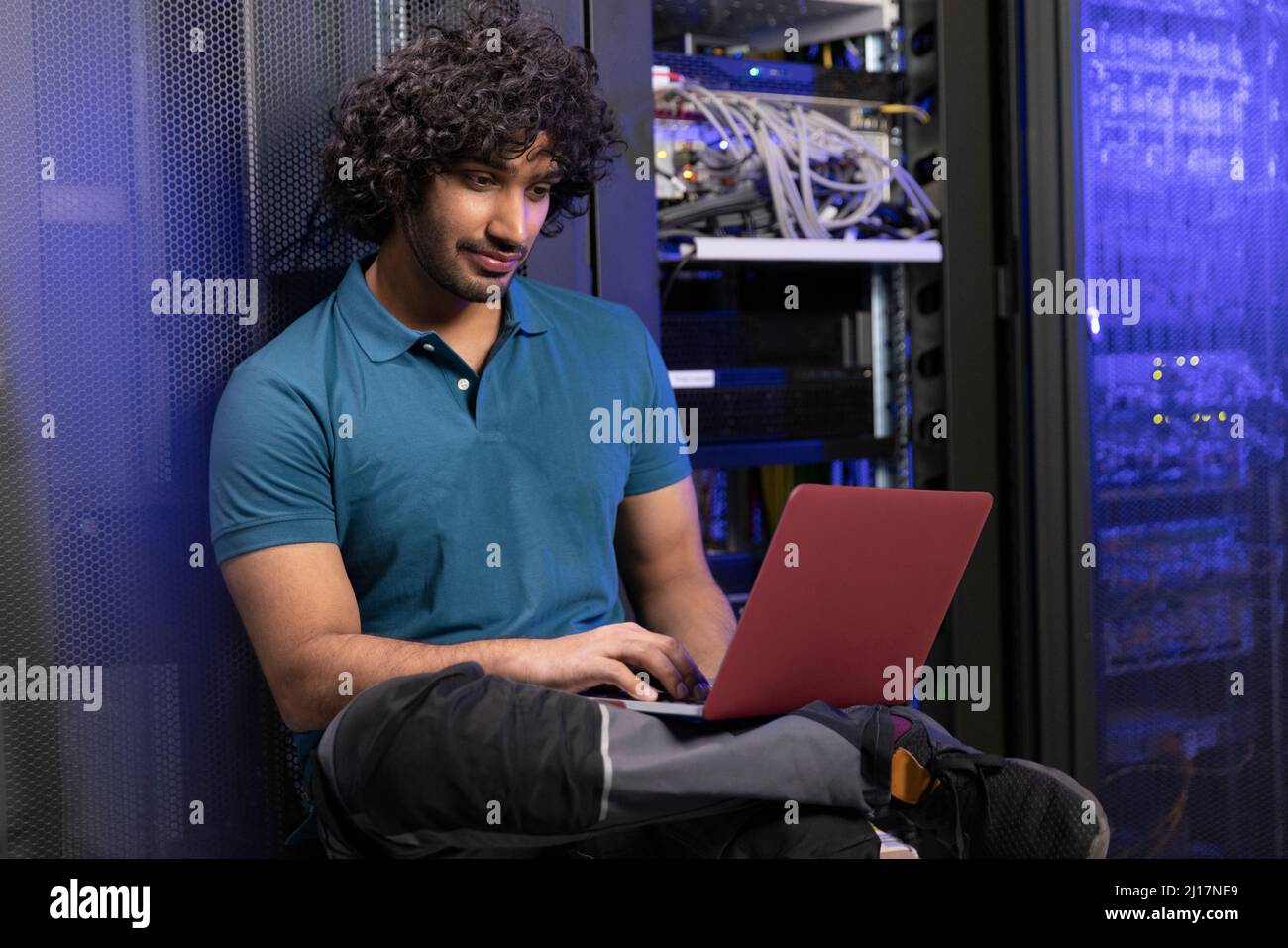 Technician using laptop sitting in server room Stock Photo - Alamy