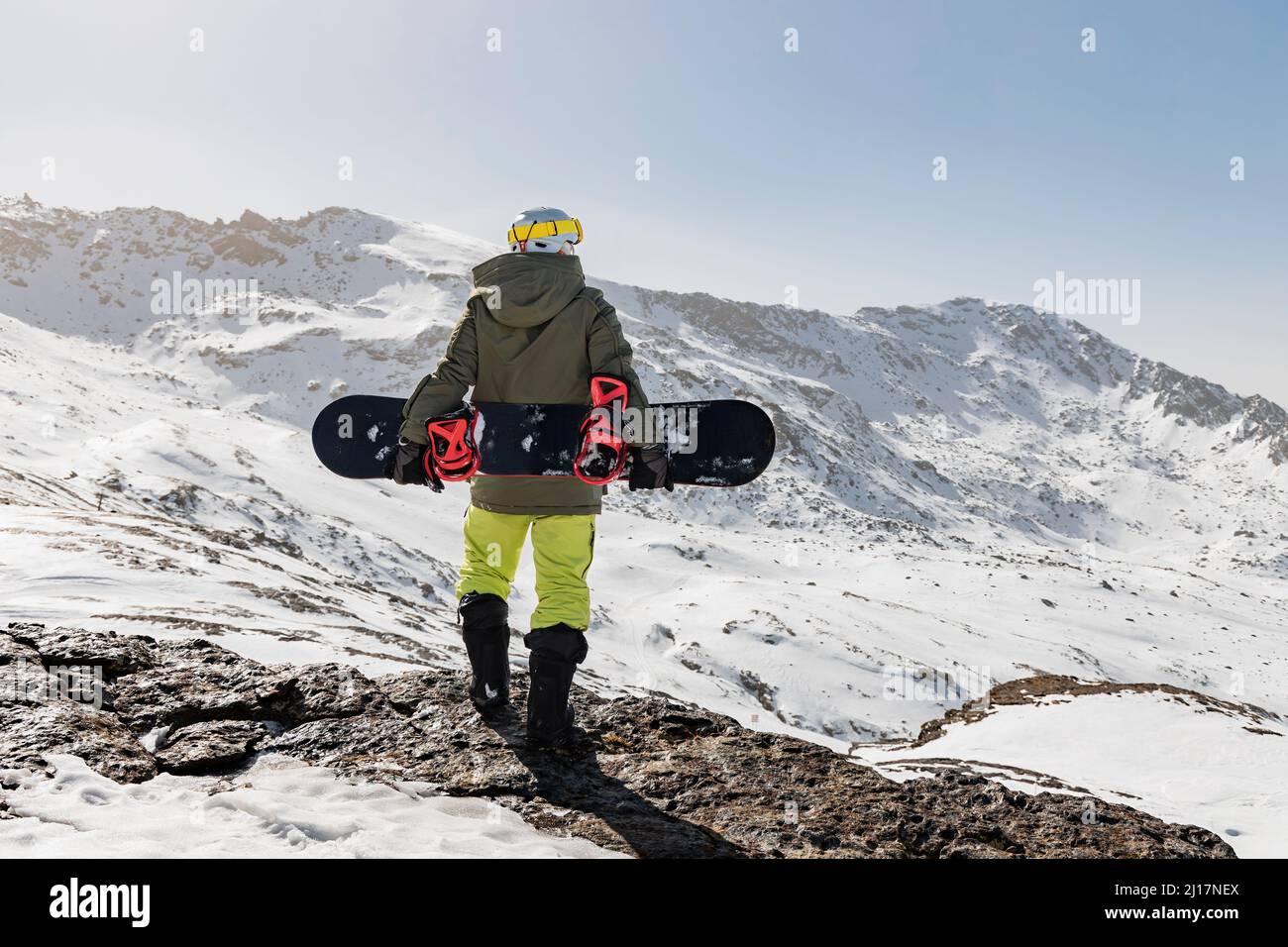 Young man standing on rock with snowboard Stock Photo - Alamy