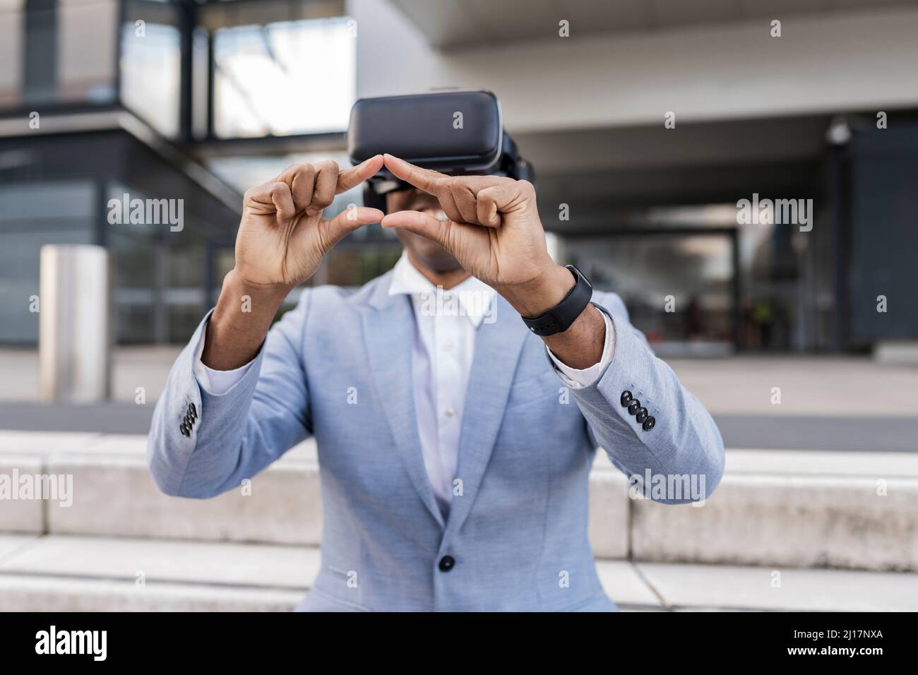 Businessman wearing virtual reality simulator gesturing sitting on ...