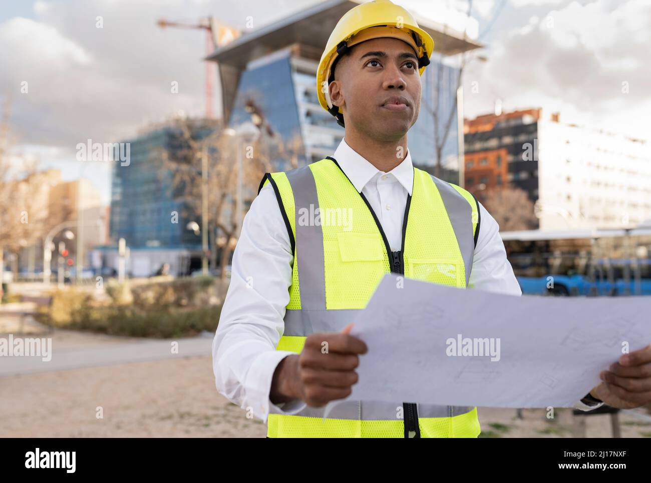Engineer holding blueprint working at construction site Stock Photo - Alamy