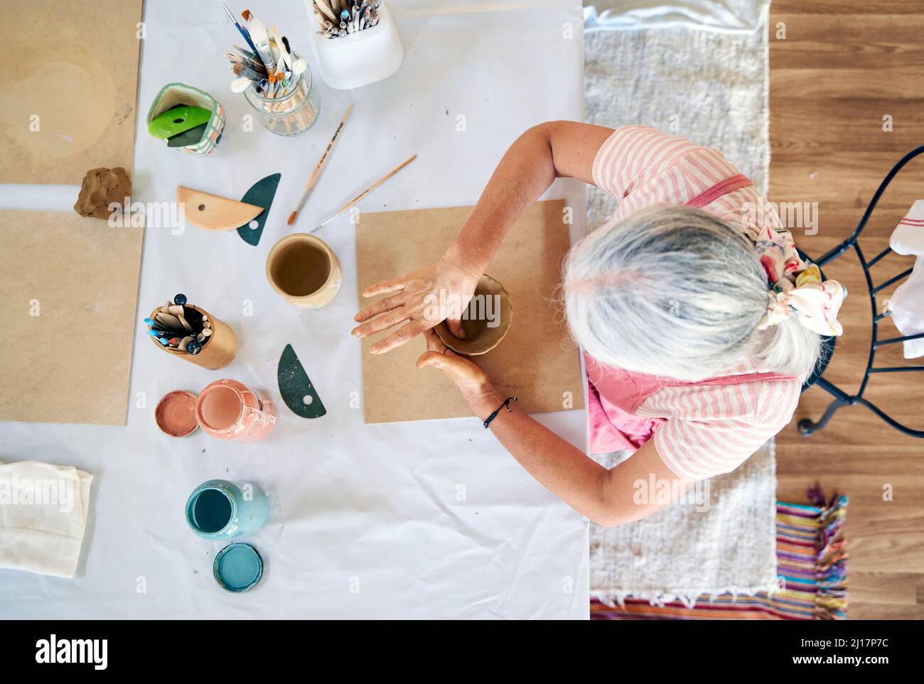 Woman making pot with clay sitting on chair at table Stock Photo - Alamy