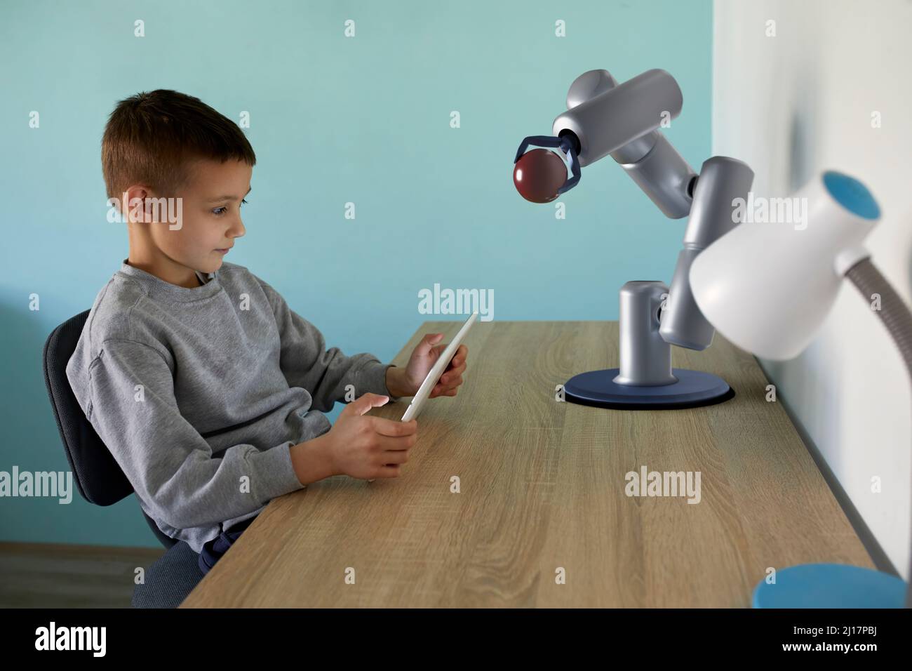 Boy controlling robotic arm through table PC at home Stock Photo - Alamy