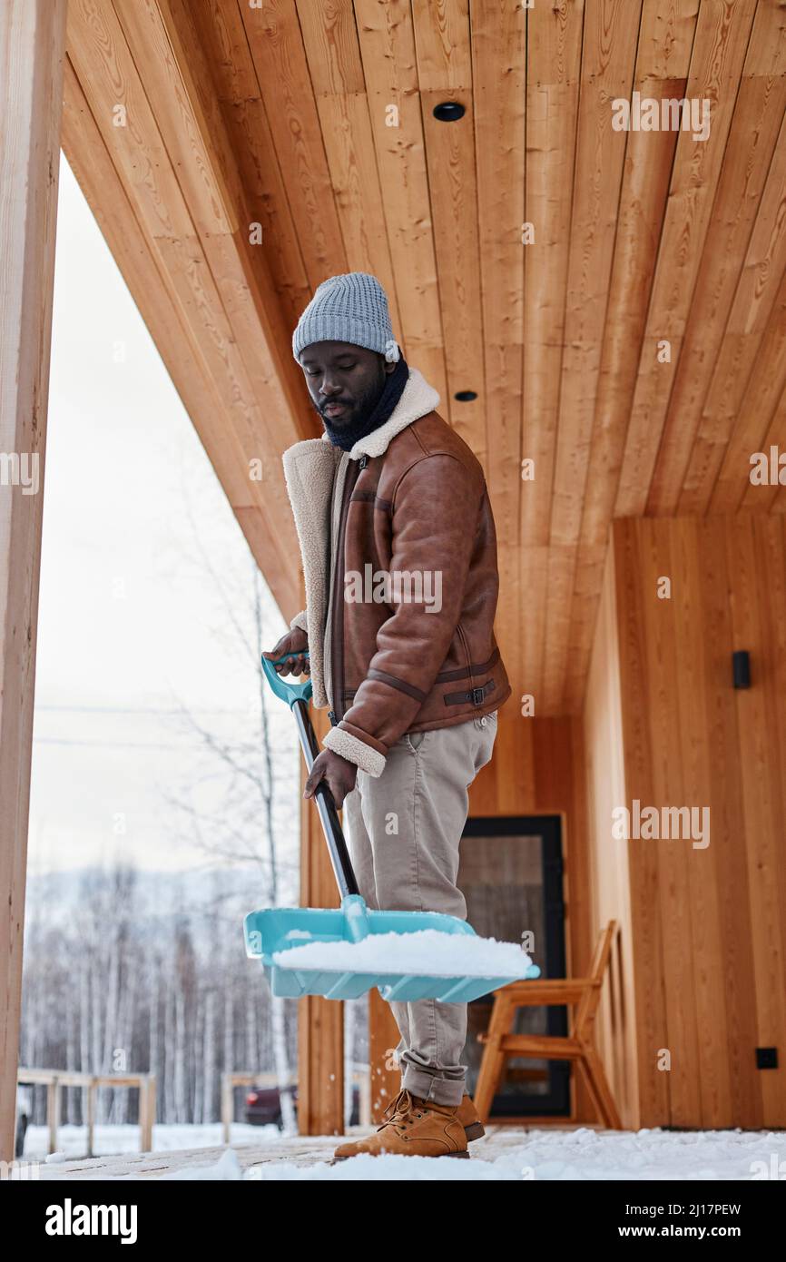 Man holding shovel with snow on porch outside house Stock Photo - Alamy