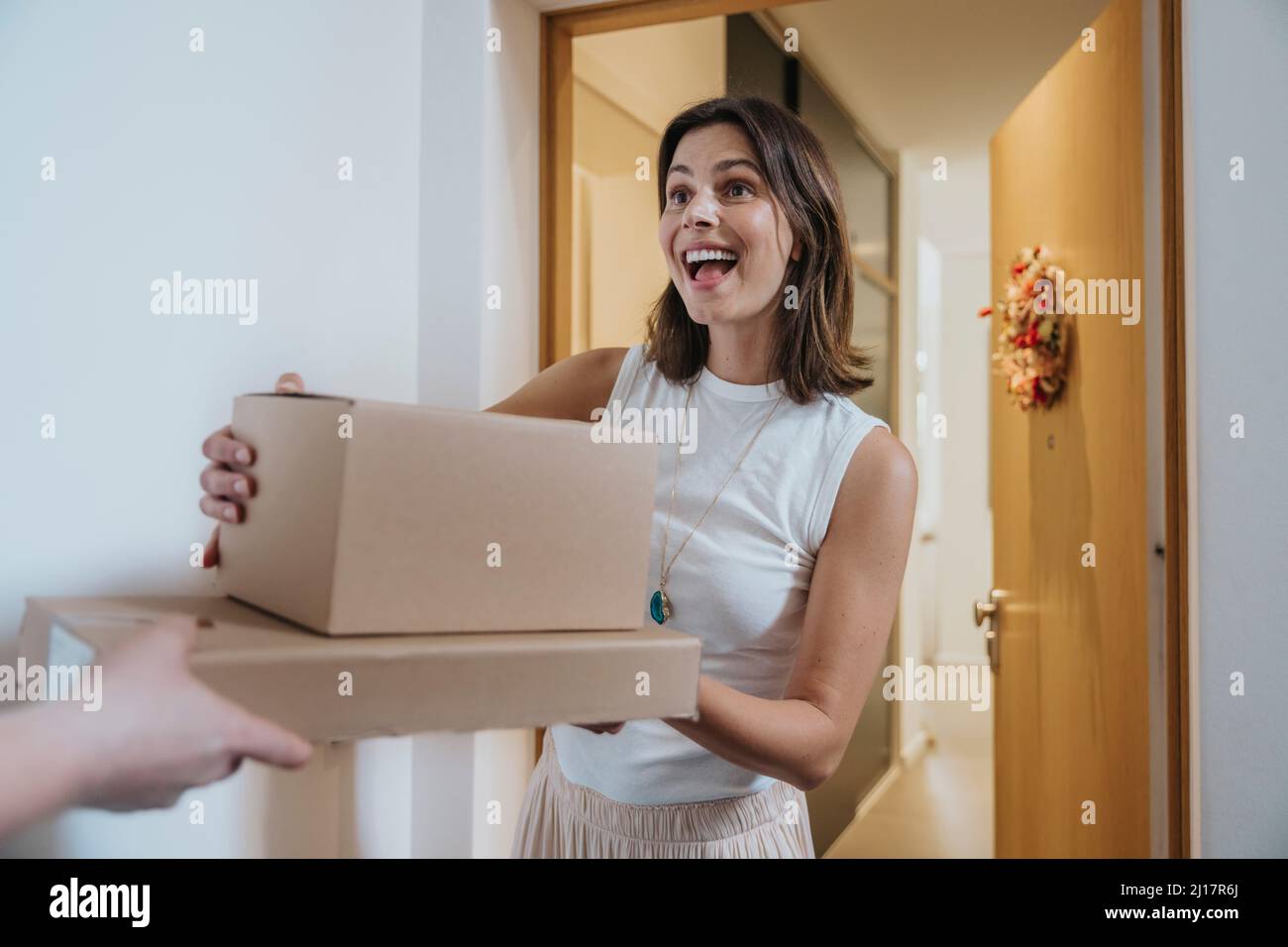 Surprise woman receiving packages from delivery person at door Stock ...