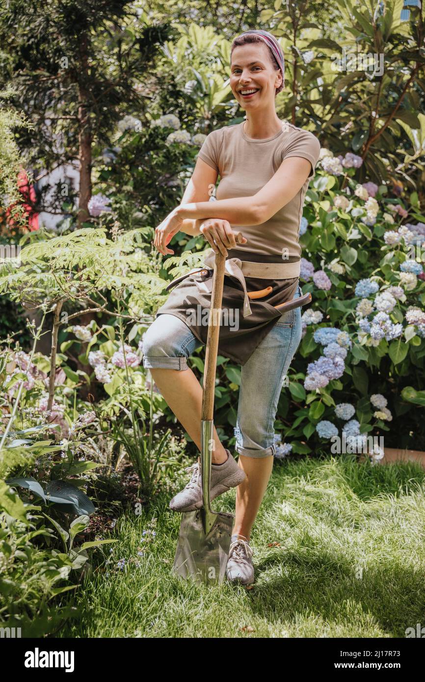 Smiling gardener standing with shovel in garden Stock Photo - Alamy