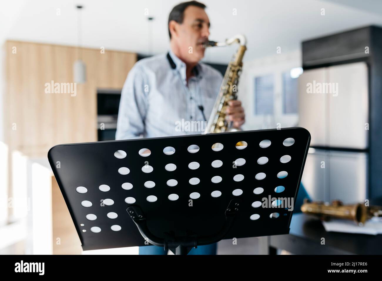Saxophonist practicing saxophone in front of musical stand at home ...