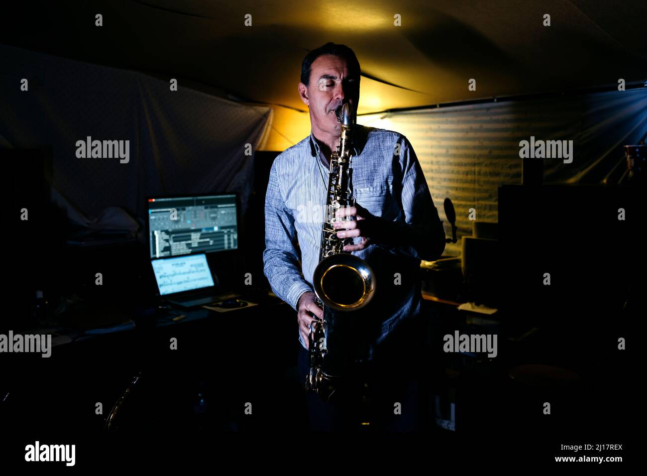 Musician with eyes closed practicing saxophone in recording studio ...