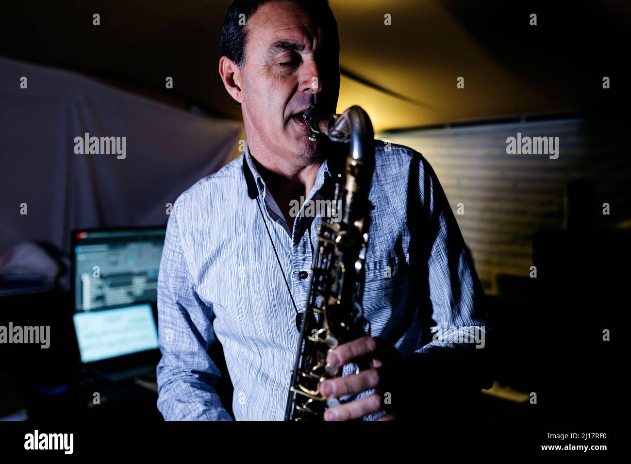 Musician with eyes closed blowing saxophone practicing in recording ...