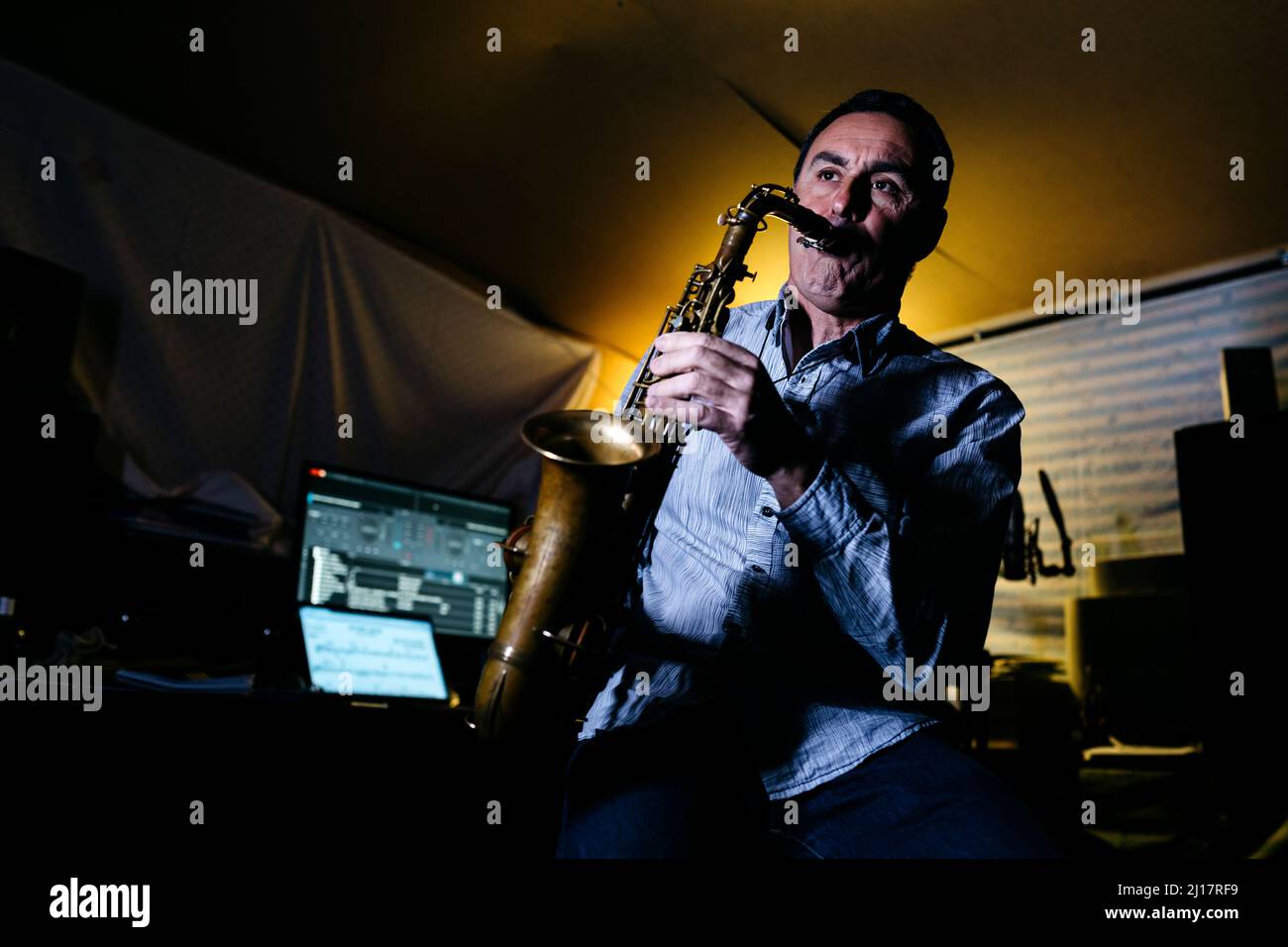 Saxophonist playing saxophone sitting in recording studio Stock Photo ...