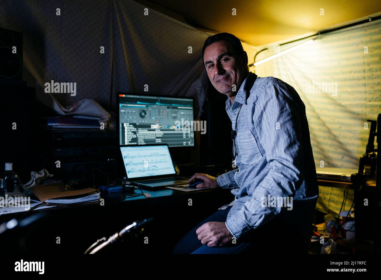 Smiling musician with laptop sitting in recording studio Stock Photo ...