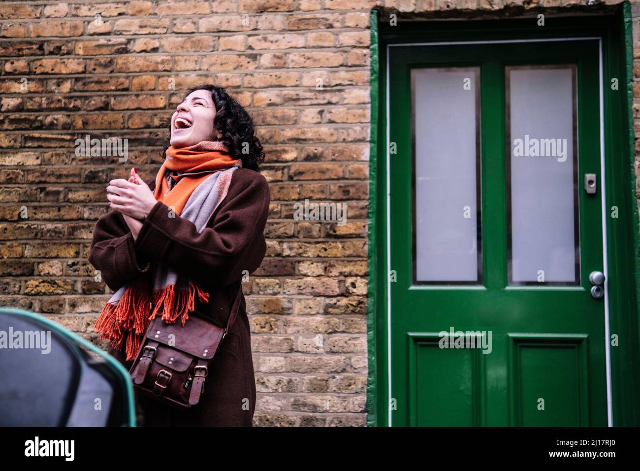 Young woman laughing in front of brick wall Stock Photo - Alamy