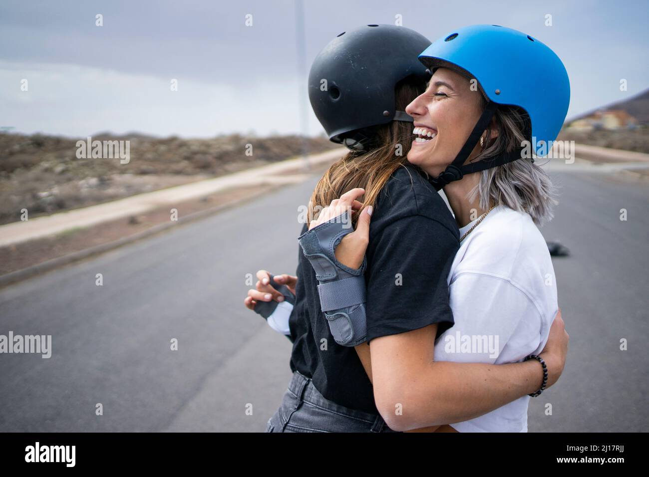 Cheerful friends wearing helmets hugging each other Stock Photo - Alamy
