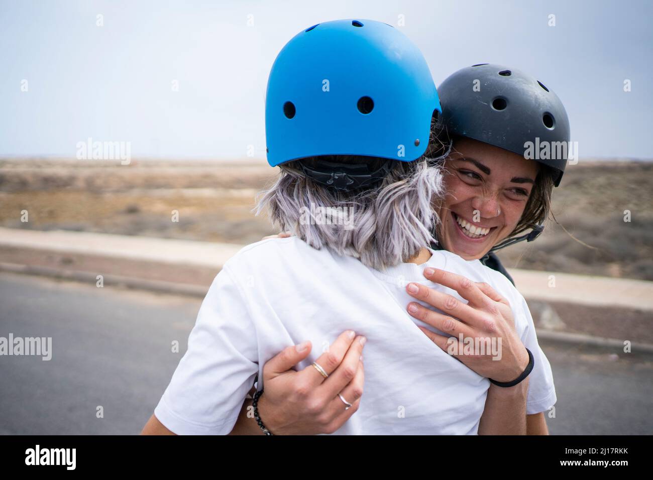 Happy friends wearing helmets hugging each other Stock Photo - Alamy