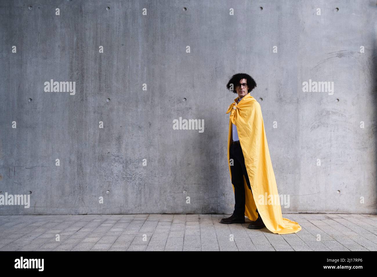 Man wearing yellow cape standing in front of gray wall Stock Photo - Alamy