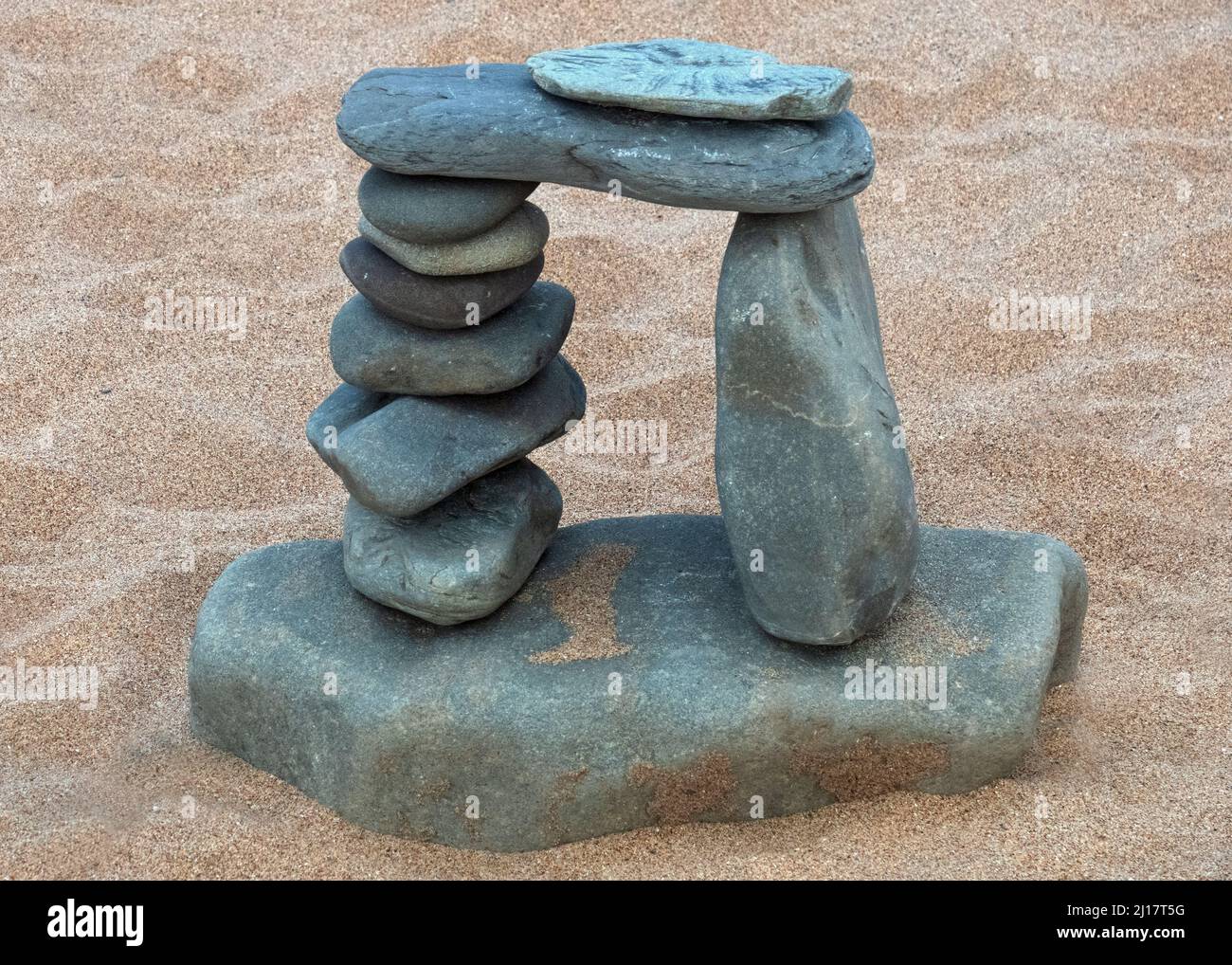 Colour photograph of coastal stones on beach stacked in almost a ...