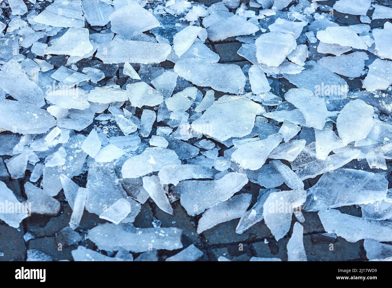 Shards of broken ice on sidewalk. View from above. Cleaning sidewalk ...