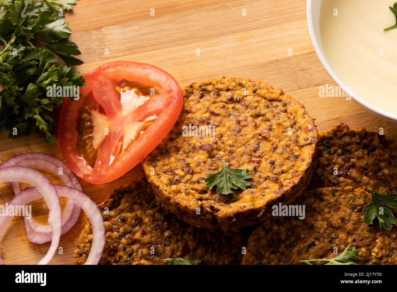 High angle view of fresh patties with tomato slice and onion rings on ...