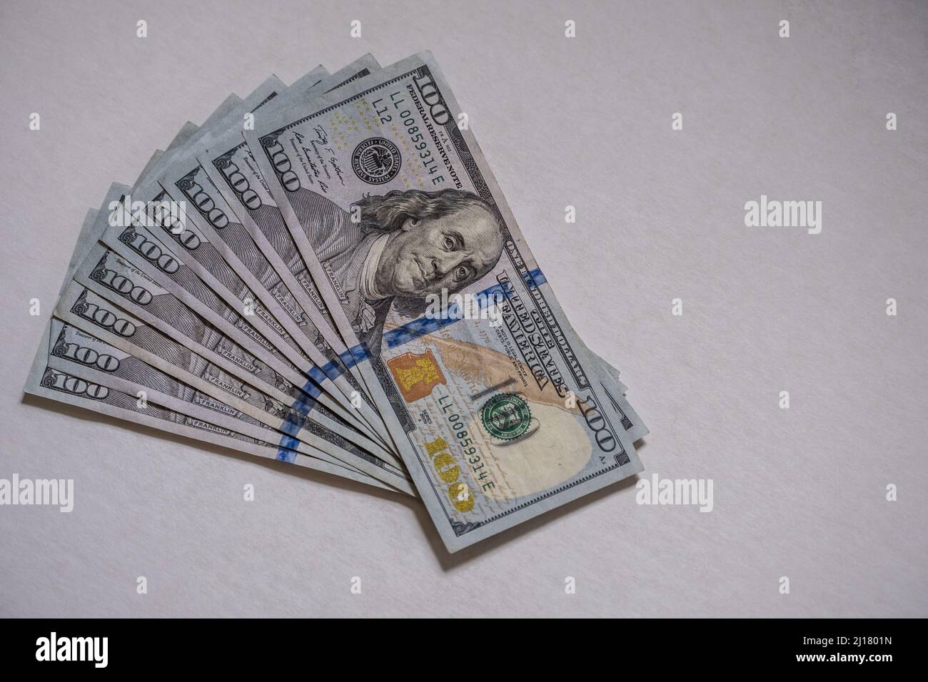 Several newer design 100 dollar bills fanned out laying flat on a white ...
