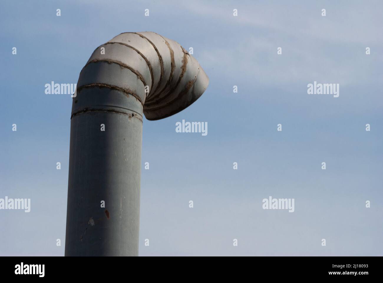 Metal chimney on roof in open-air factory with blue sky and natural ...