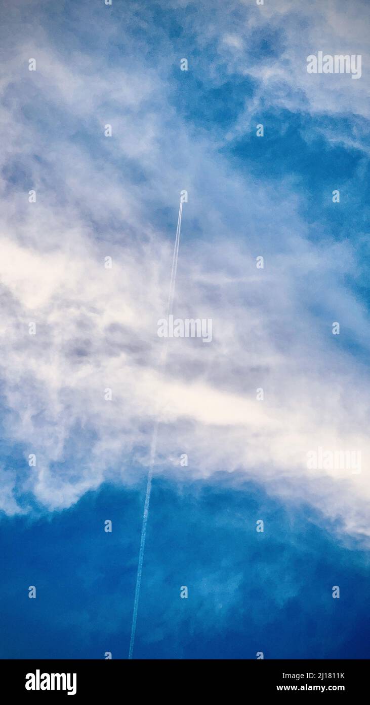 The beautiful vertical shot of an airplane crossing the blue-white ...