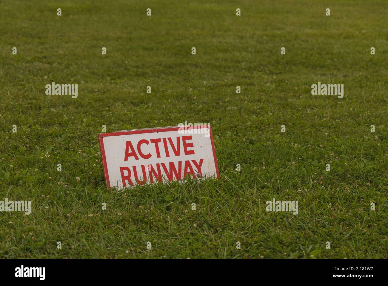 A red and white 'Active runway' sign in the green grass Stock Photo - Alamy