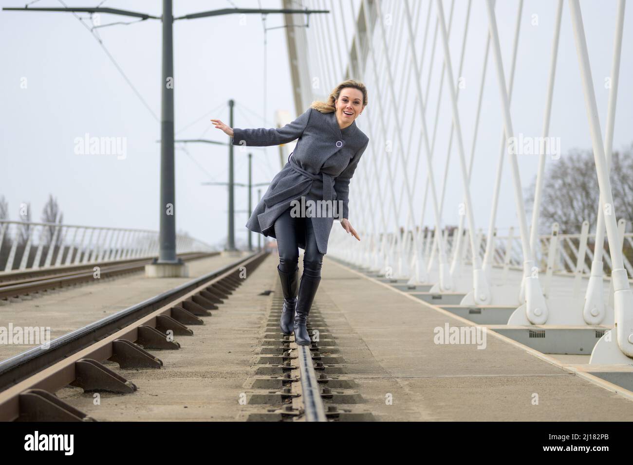 Attractive fun loving middle-aged woman crossing a rail bridge ...