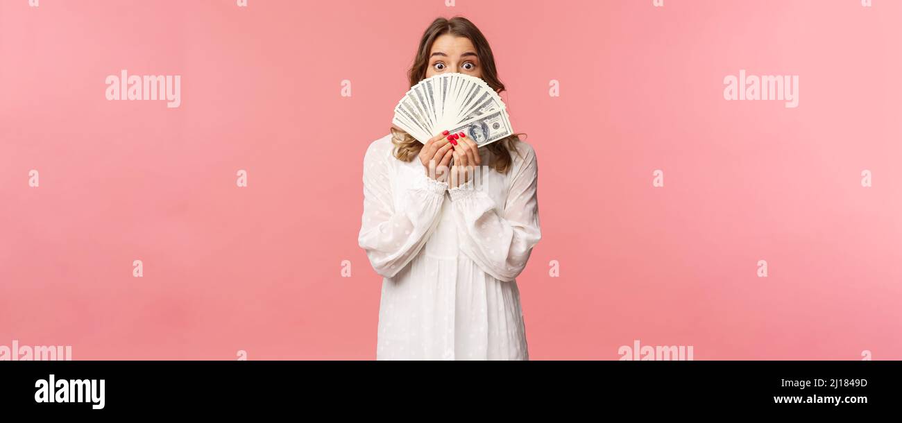 Portrait of amazed and excited cute feminine blond girl in white dress ...