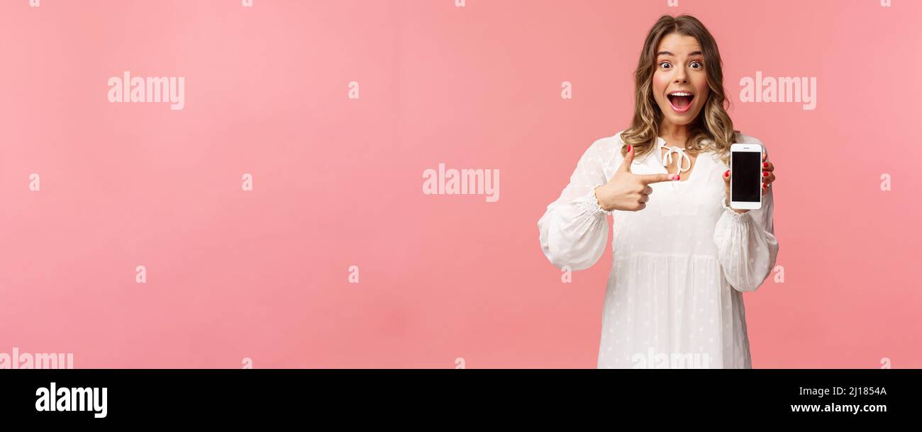 Portrait of impressed, excited young blond woman showing something ...