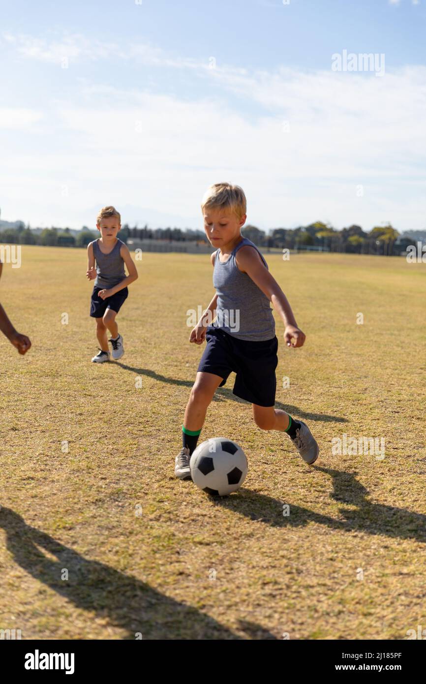Full length of caucasian elementary schoolboys playing soccer on soccer ...