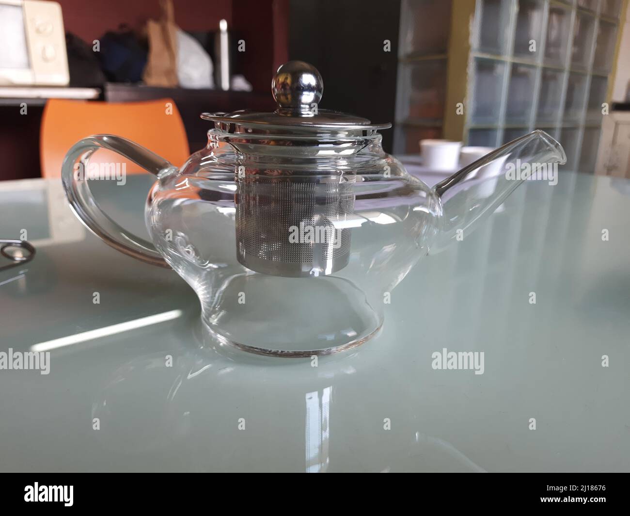 A closeup of man made glass jug and metal tea filter in it on the glass ...