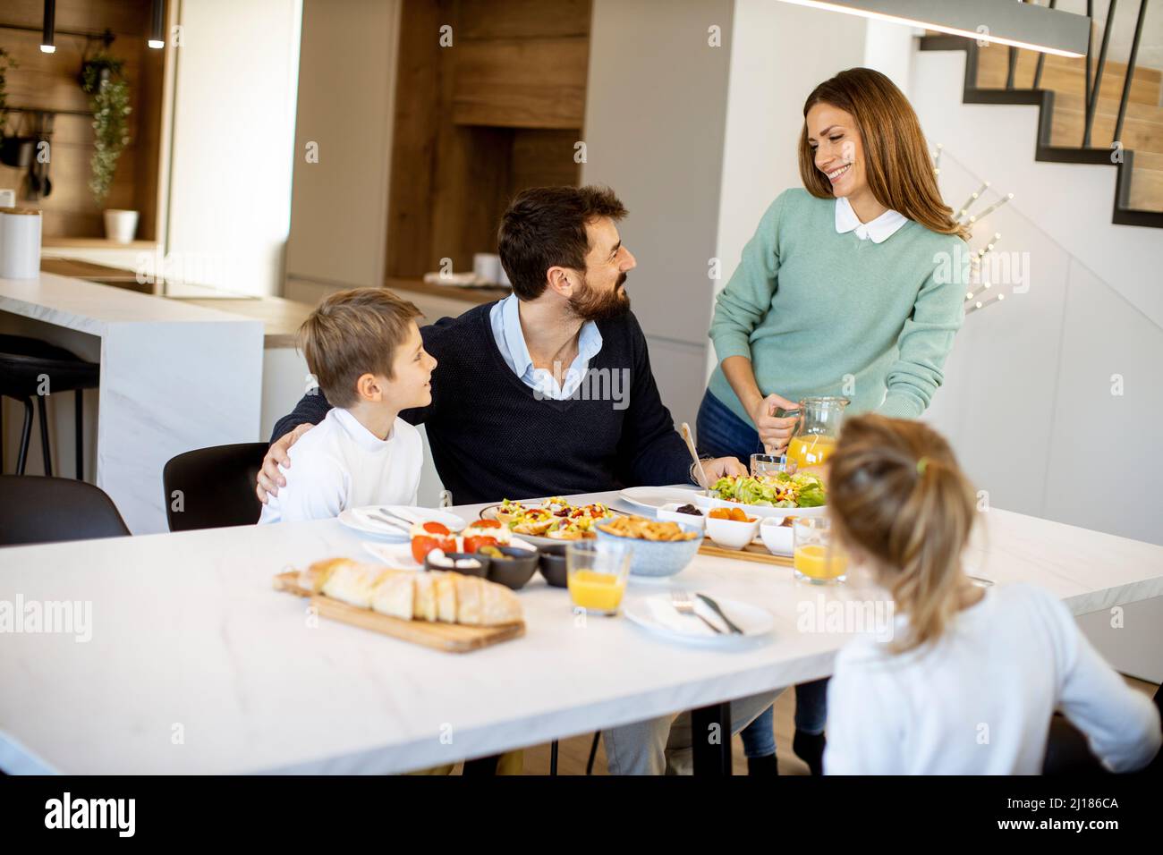 Young mother preparing breakfast for her family in the modern kitchen ...