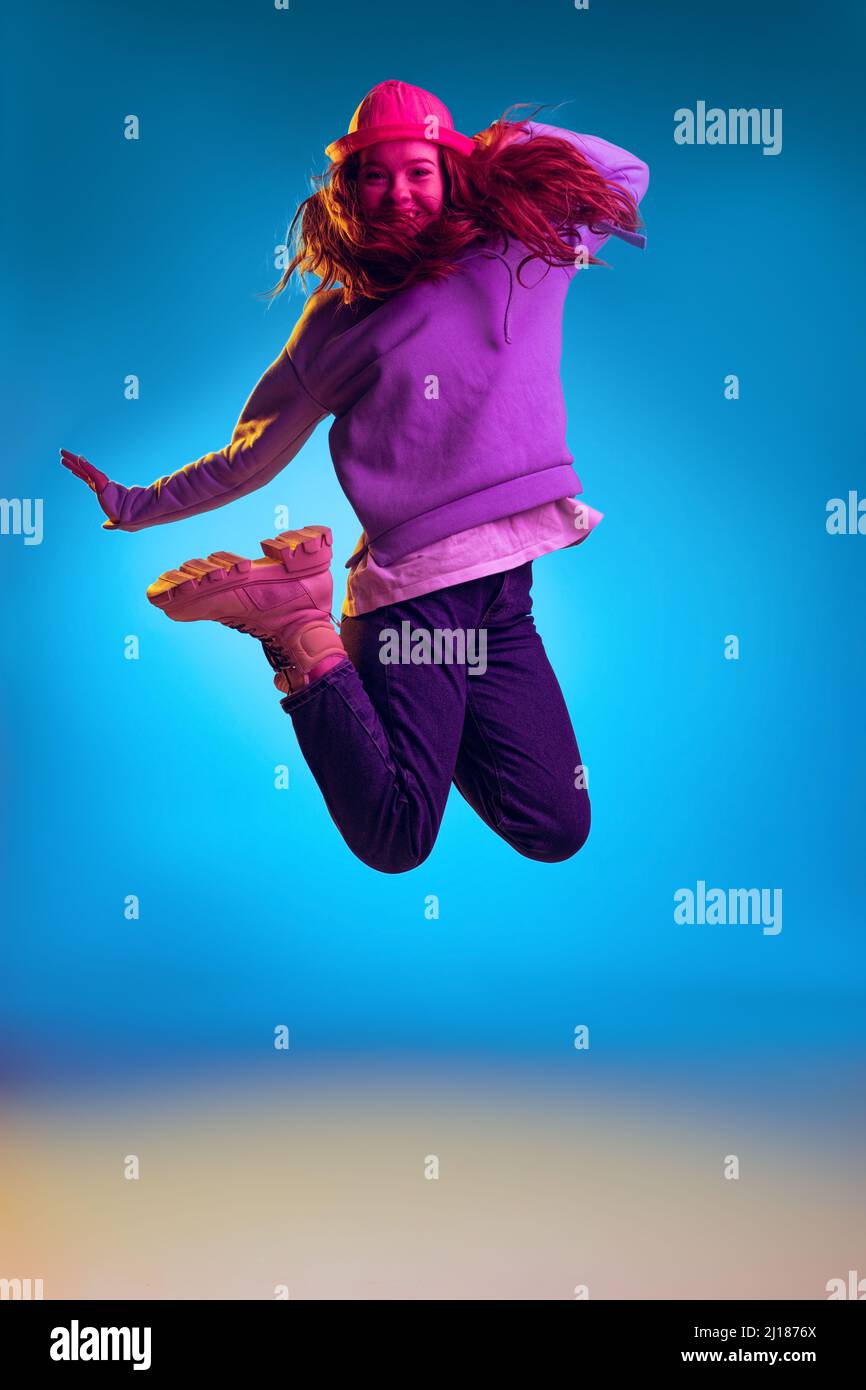 Portrait of young stylish girl posing in a jump isolated over blue ...