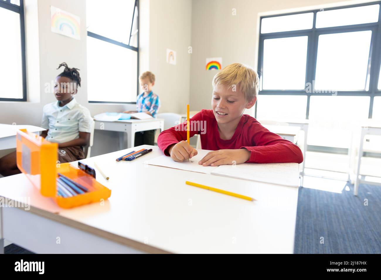 Multiracial elementary schoolboys studying at desk in classroom Stock ...