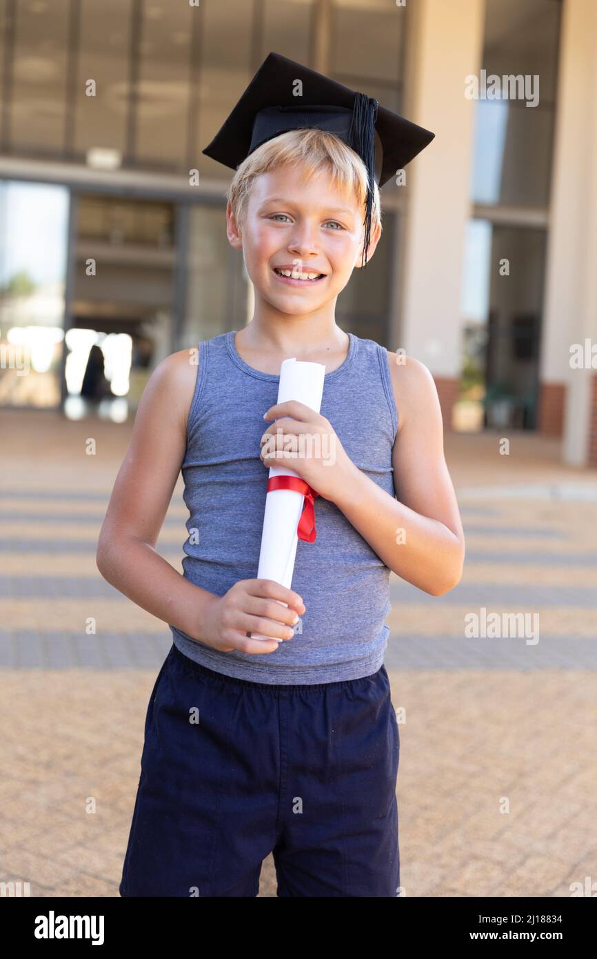 Portrait of happy caucasian elementary schoolboy with mortarboard and ...
