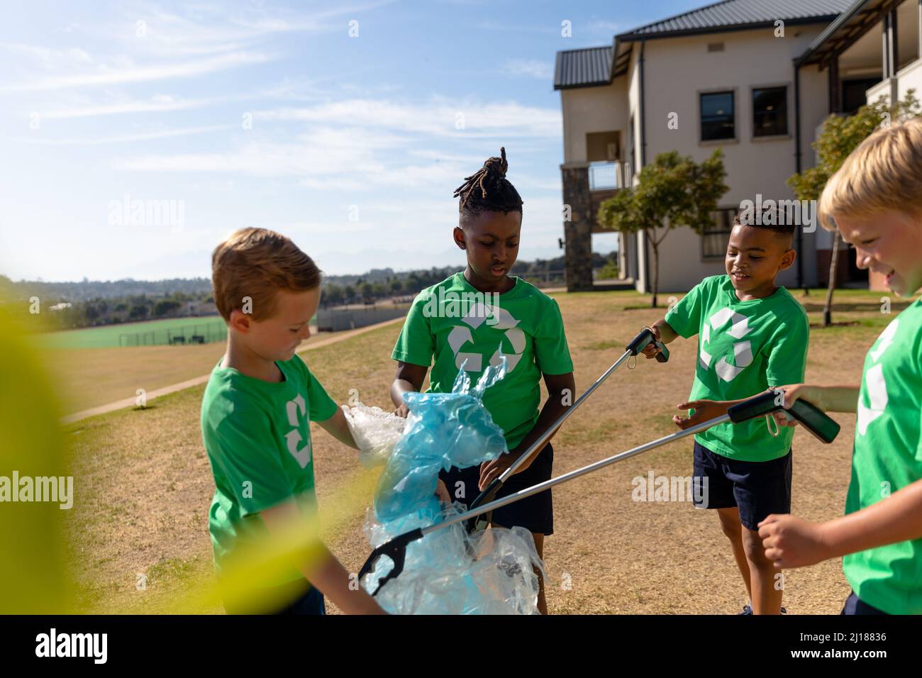 Multiracial elementary schoolboys recycling plastic in garbage bag at ...