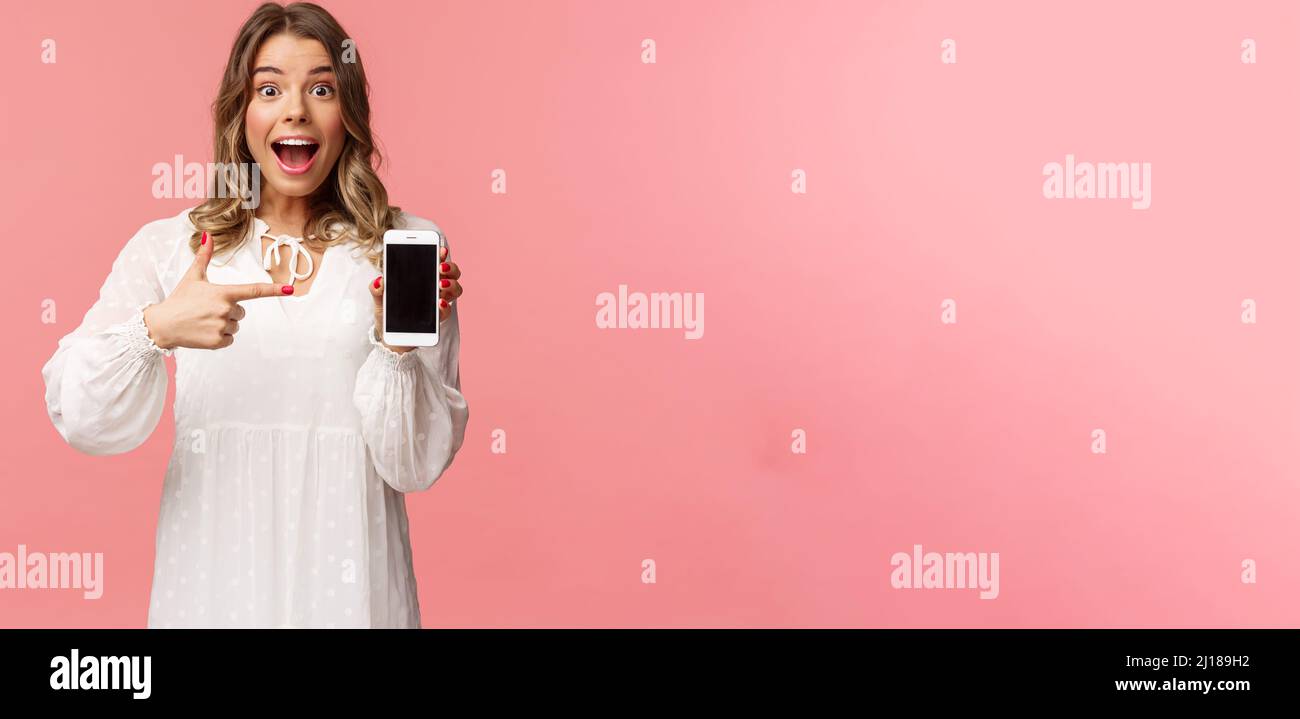 Portrait of impressed, excited young blond woman showing something ...