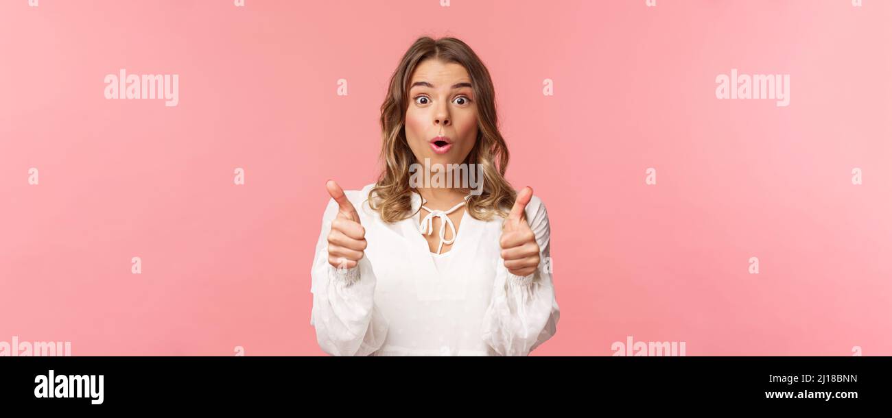 Close-up portrait of impressed blond girl showing thumbs-up look ...