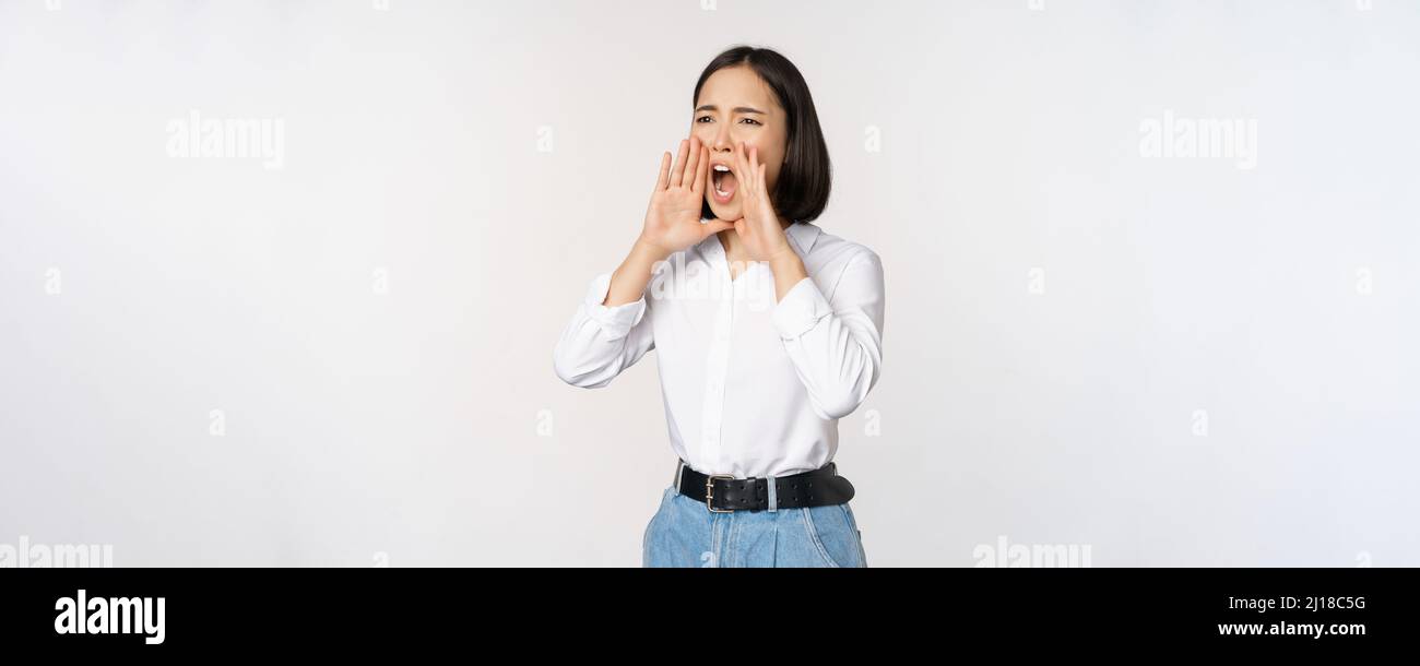 Image of young asian woman calling for someone, shouting loud and ...