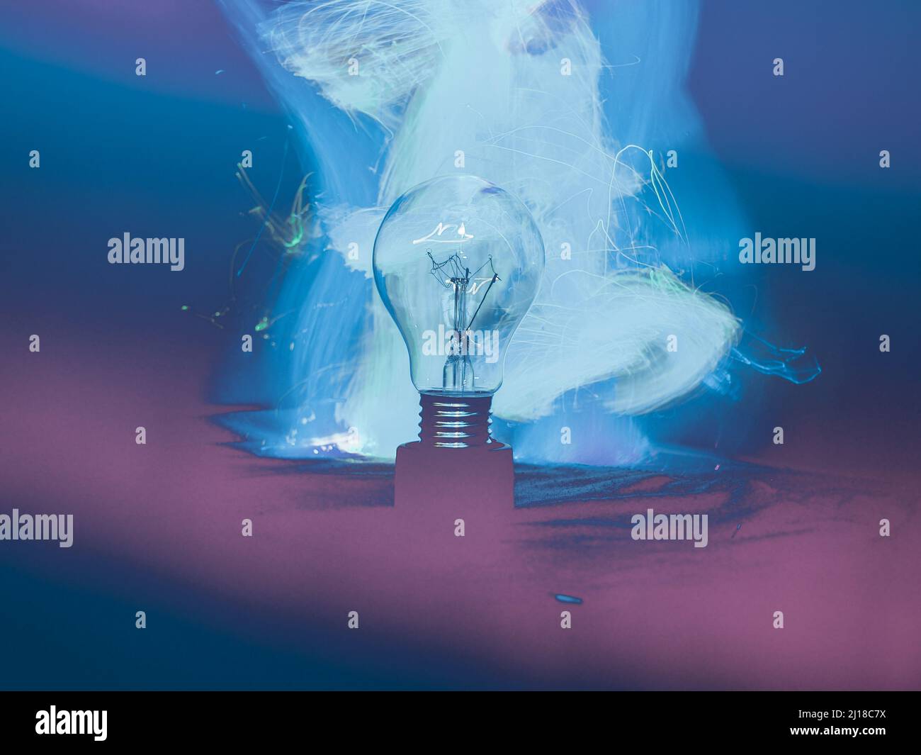 A blue bursts of light from behind a light bulb on a pink background ...