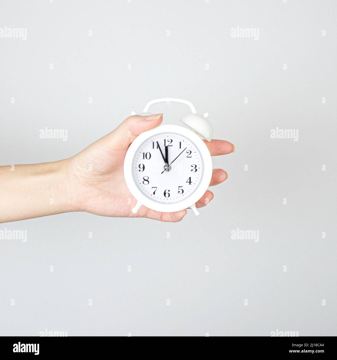 Hand holds little white alarm clock in hand, shows how much time left ...