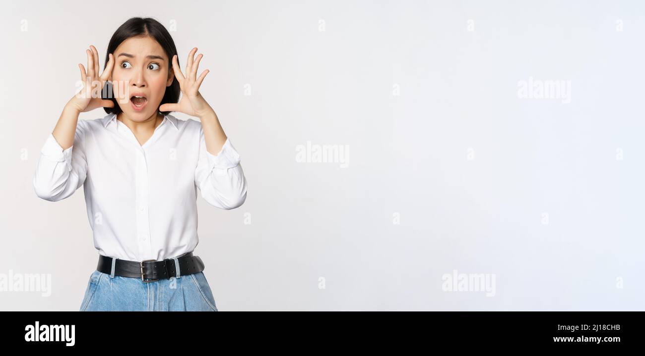 Image of shocked anxious asian woman in panic, holding hands on head ...