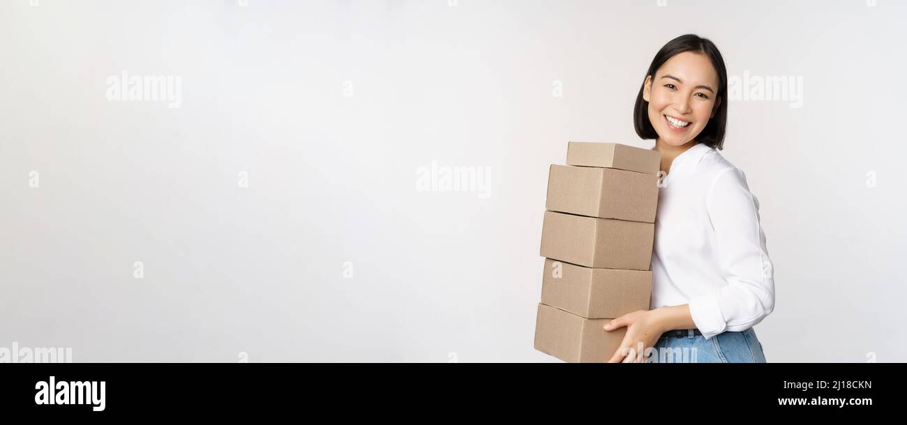 Portrait of young asian woman holding boxes, carry delivery goods ...
